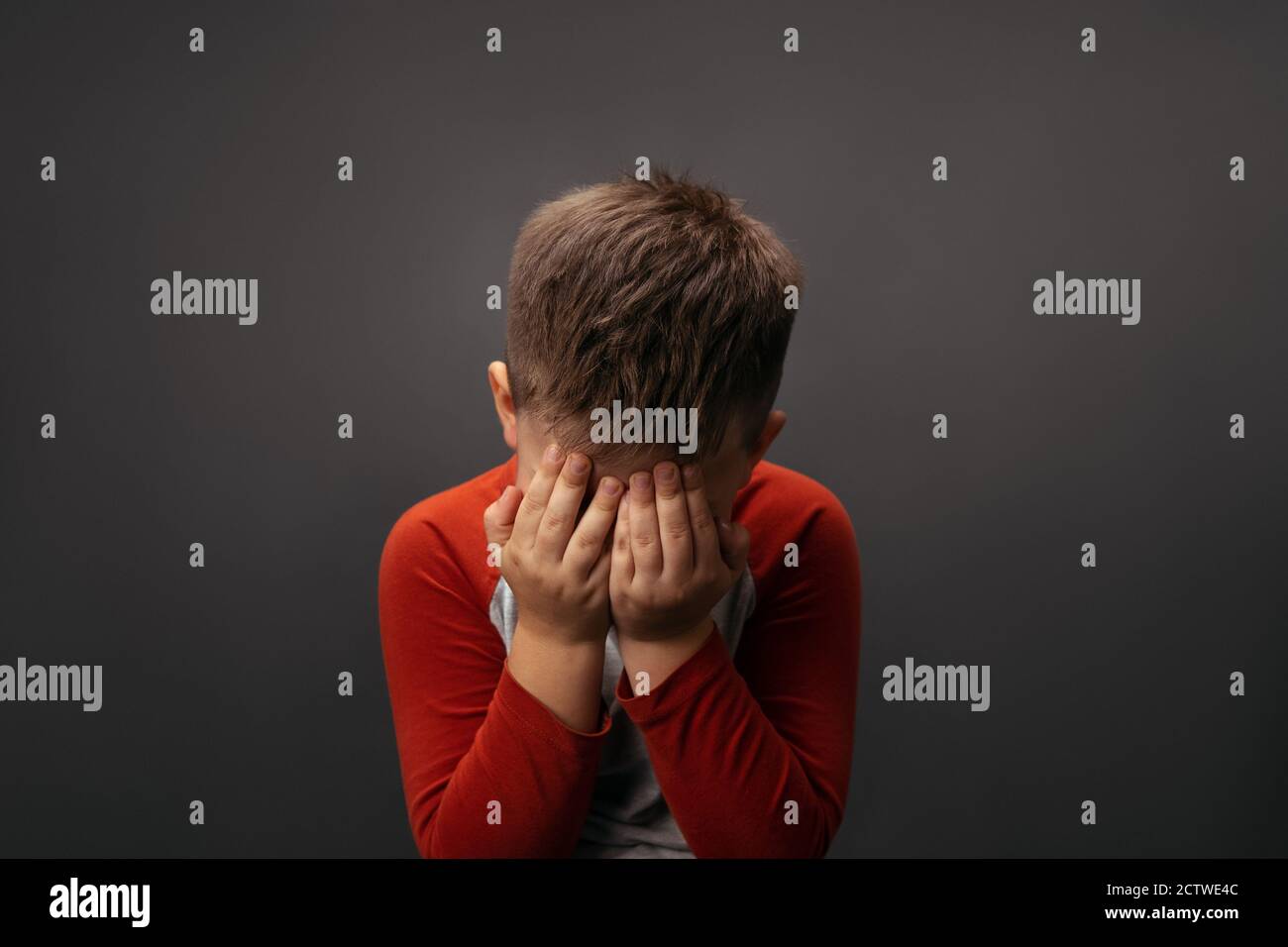 Sad boy cries in the studio. He covered his face with his hands ...