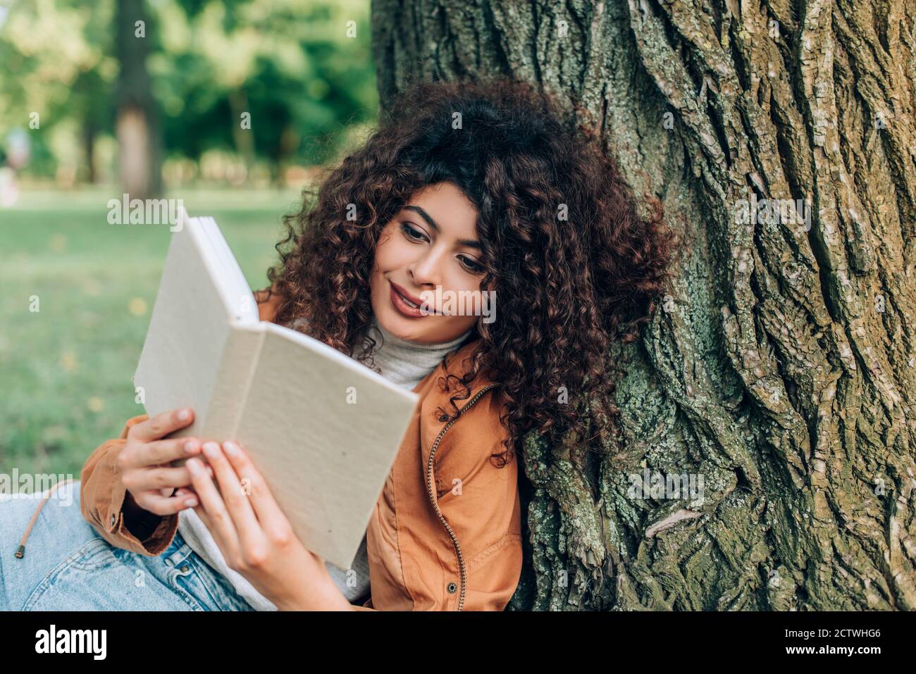 Woman reading book grass tree hi-res stock photography and images - Alamy