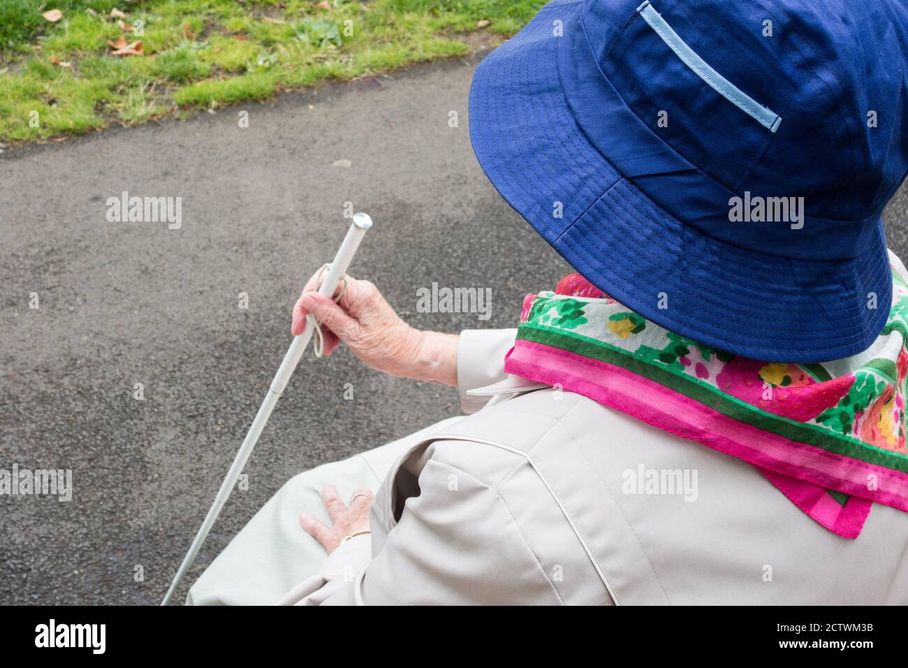 Ninety year old visually impaired lady with white stick sitting on ...