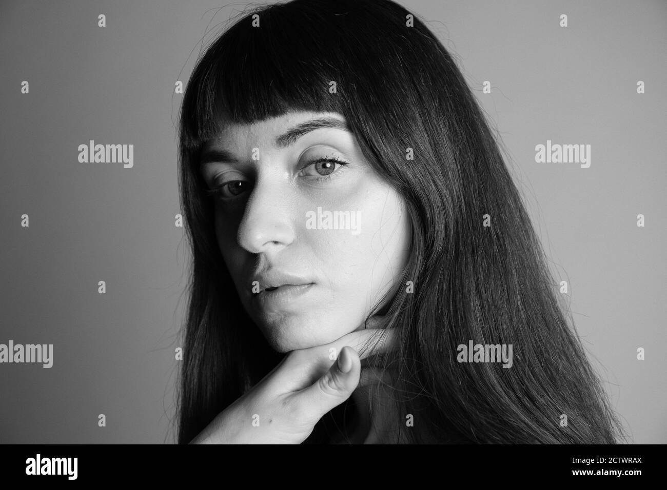 Close up studio portrait of a pretty brunette woman, hand on the chin ...