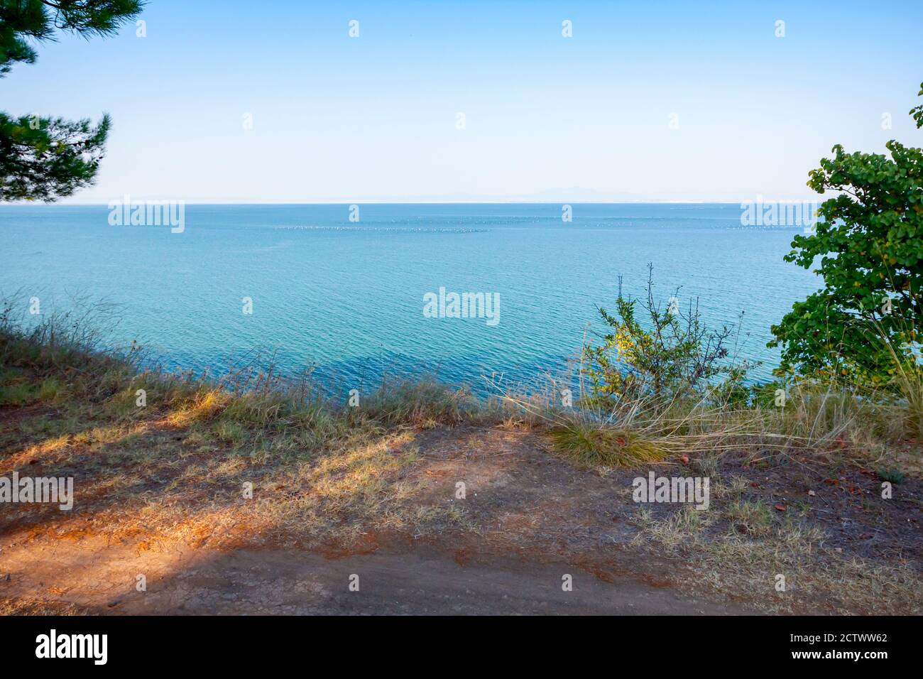 Rocky cliff with vegetation above peaceful bay and farm of seashells ...
