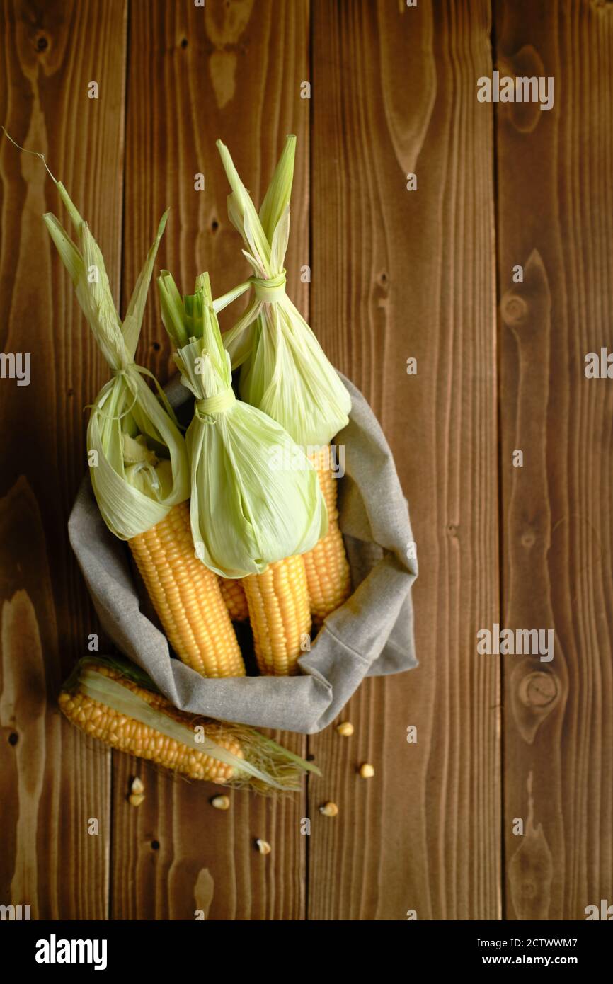 Top view shot of opened fresh corncobs with husks in a sack with a ...