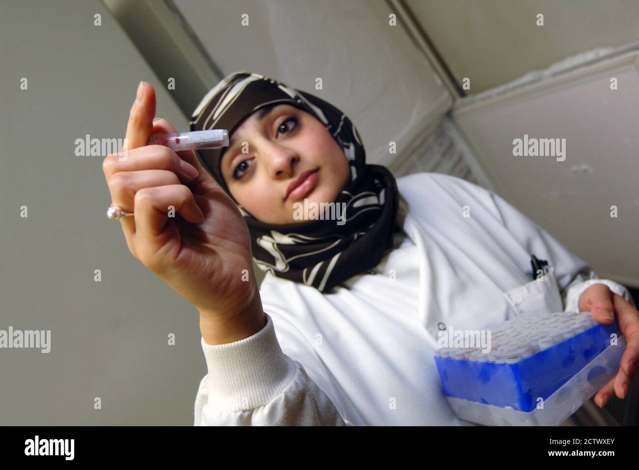 A hospital lab technician holds up a frozen test tube; with a sample of ...