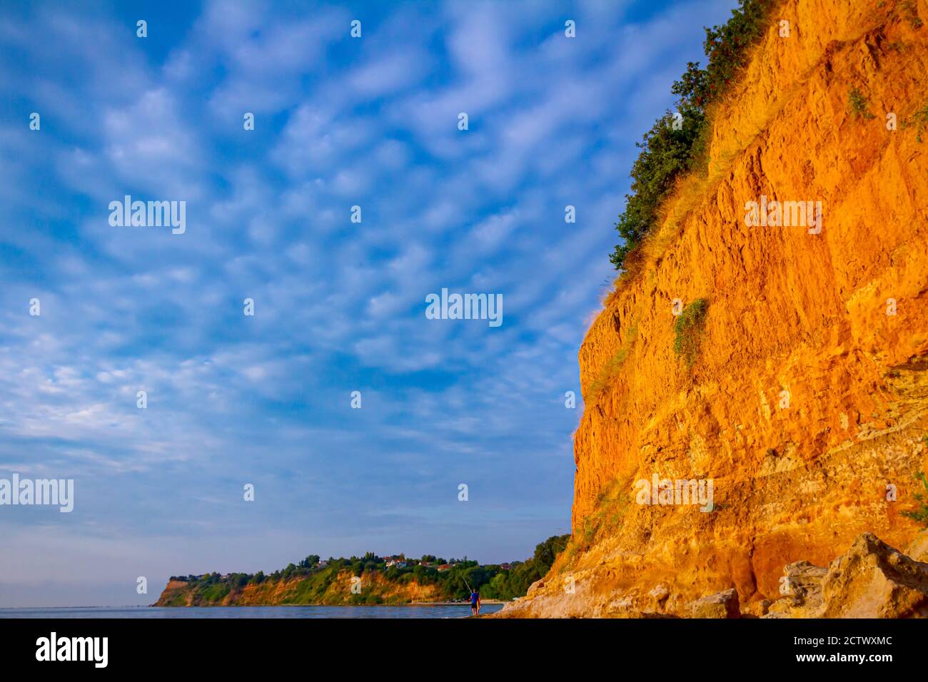 View on the big overgrown rocky cliff beside the sea water. Settlement ...