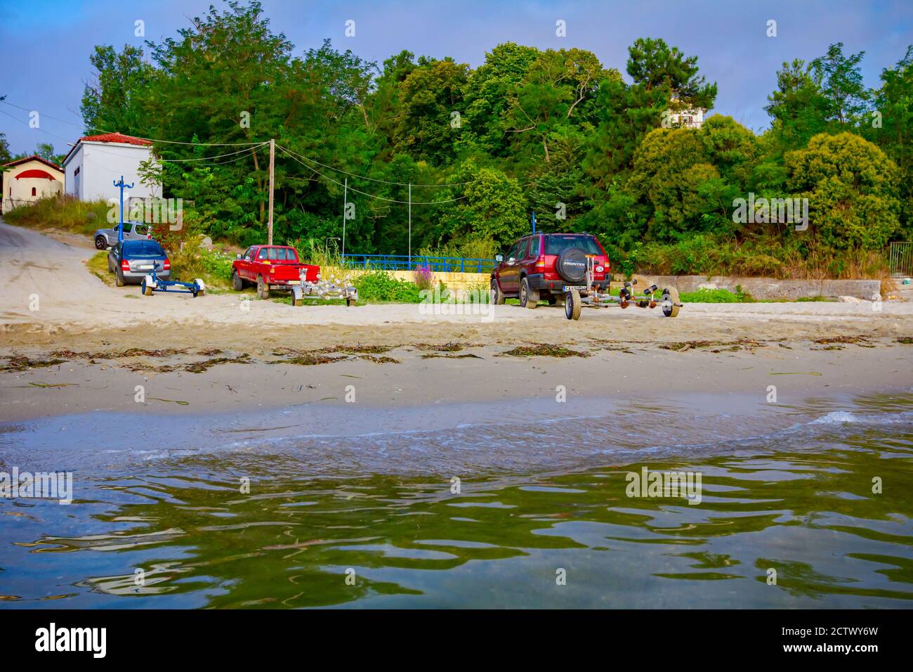 Several cars are parked on the beach with trailers for transport boats ...
