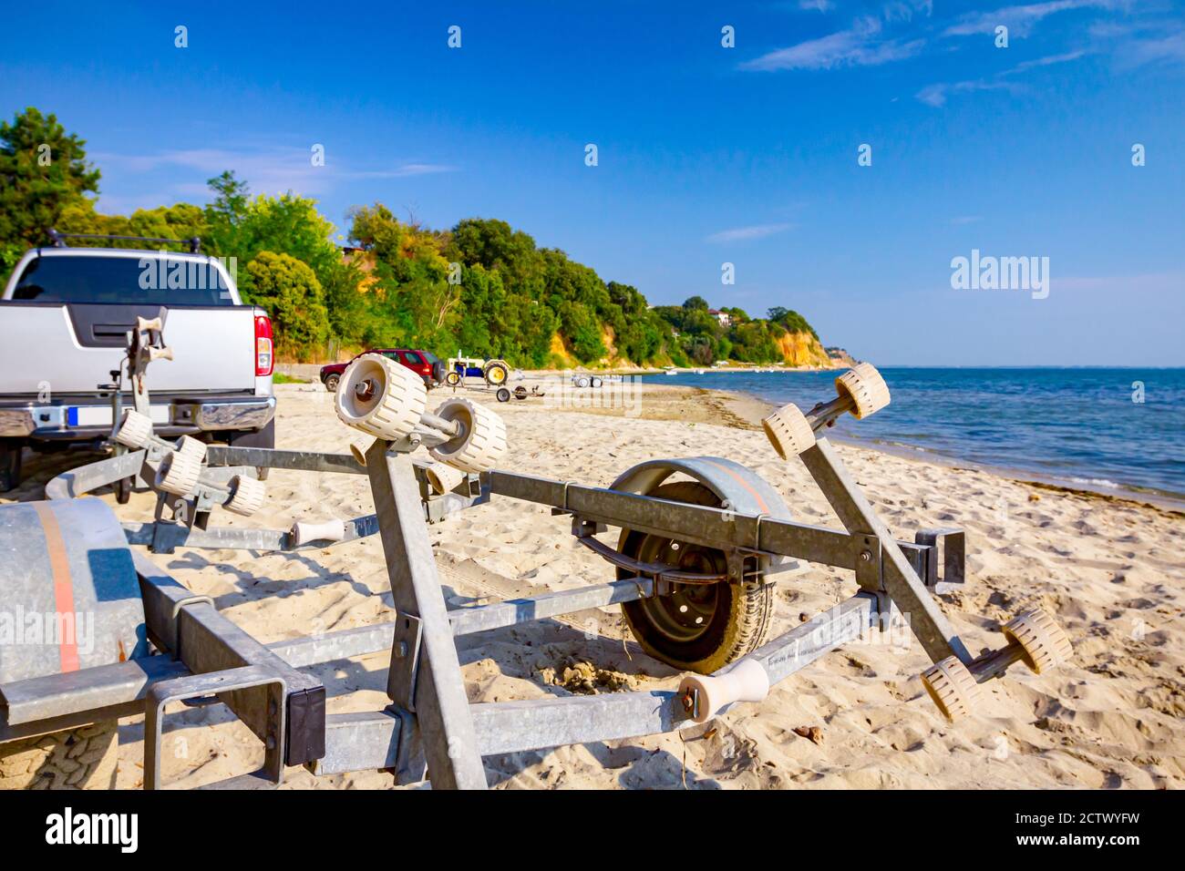 Several cars are parked on the beach with trailers for transport boats ...