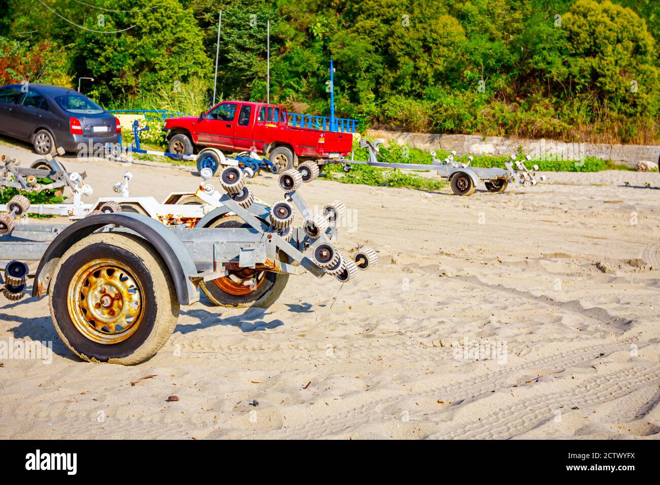 Several cars are parked on the beach with trailers for transport boats ...