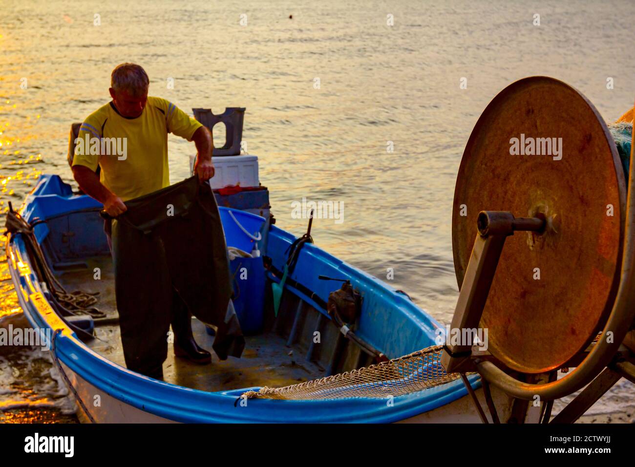 Fisherman in motor boat spreads rubber trousers, prepares his clothes ...