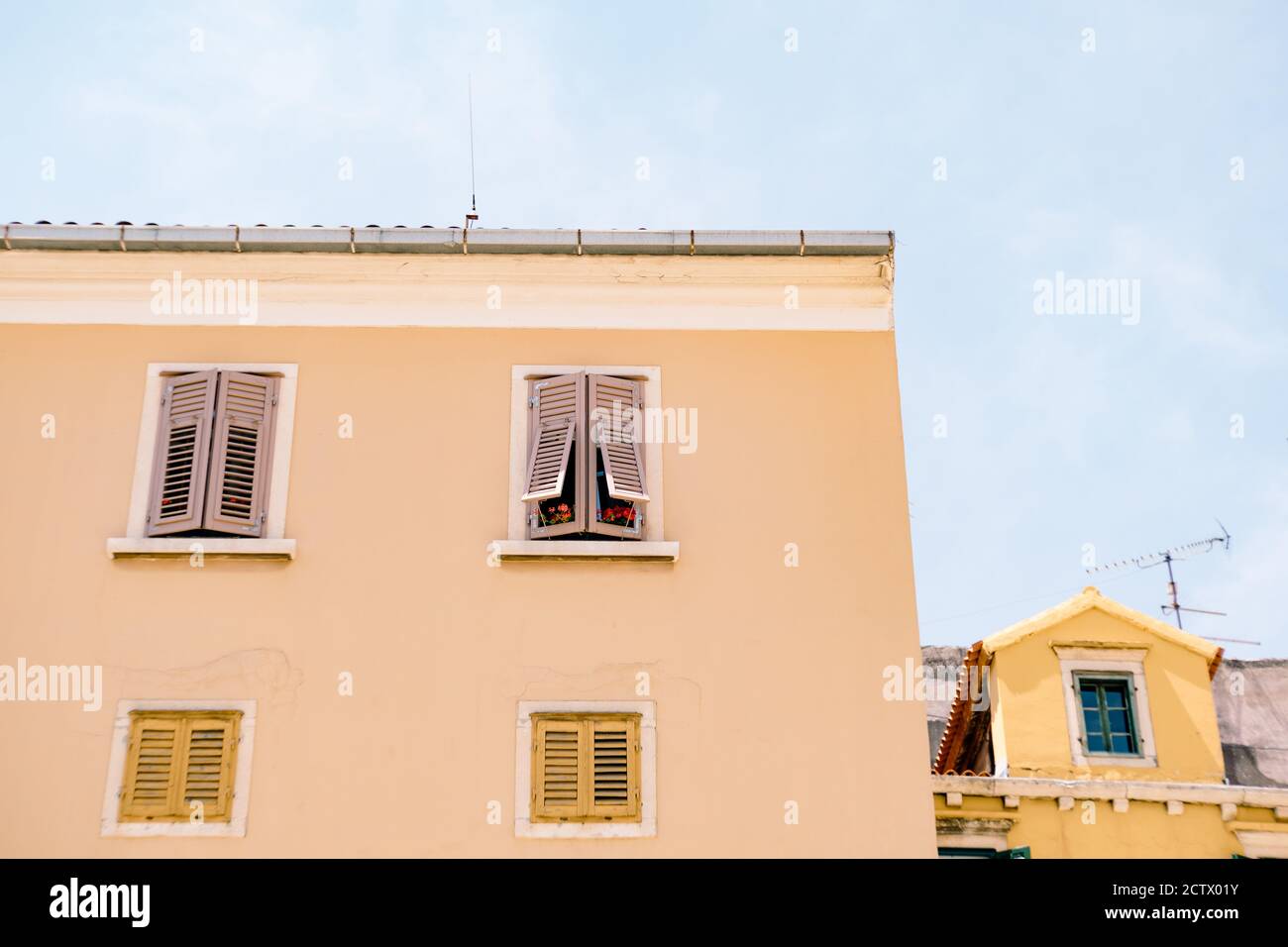 Residential building in beige color with windows and open shutters ...