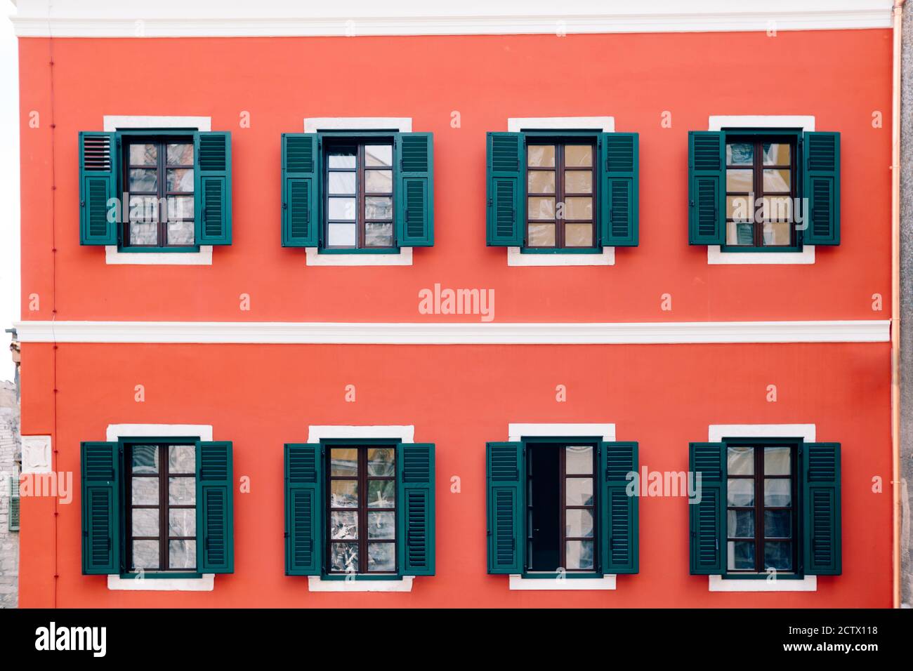 A bright pink home with brown window frames and open green shutters ...