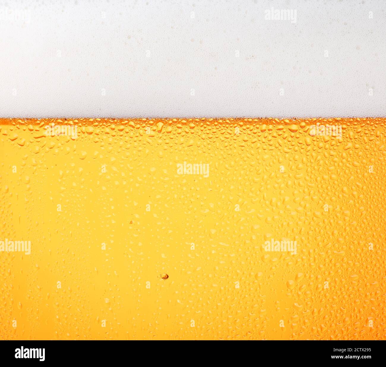 Close up background texture of pouring lager beer with bubbles and ...