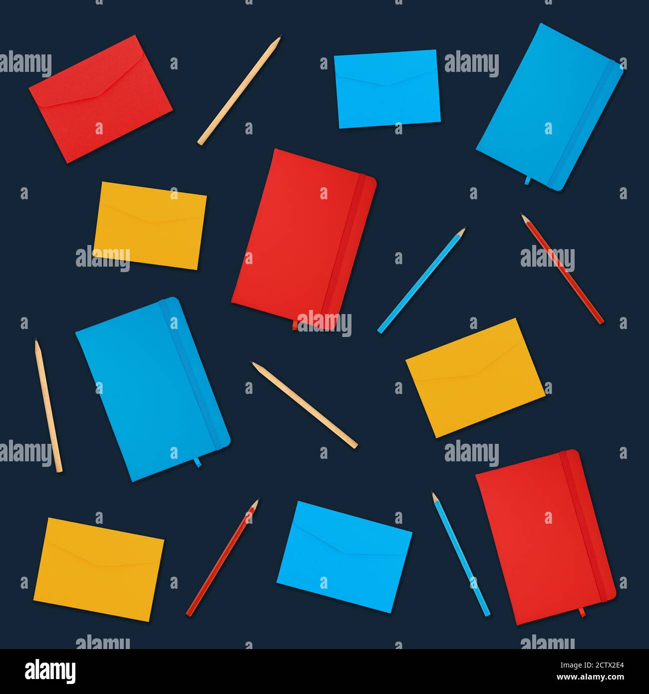 Pattern of multicolor notebooks, paper envelopes and pencils over dark ...