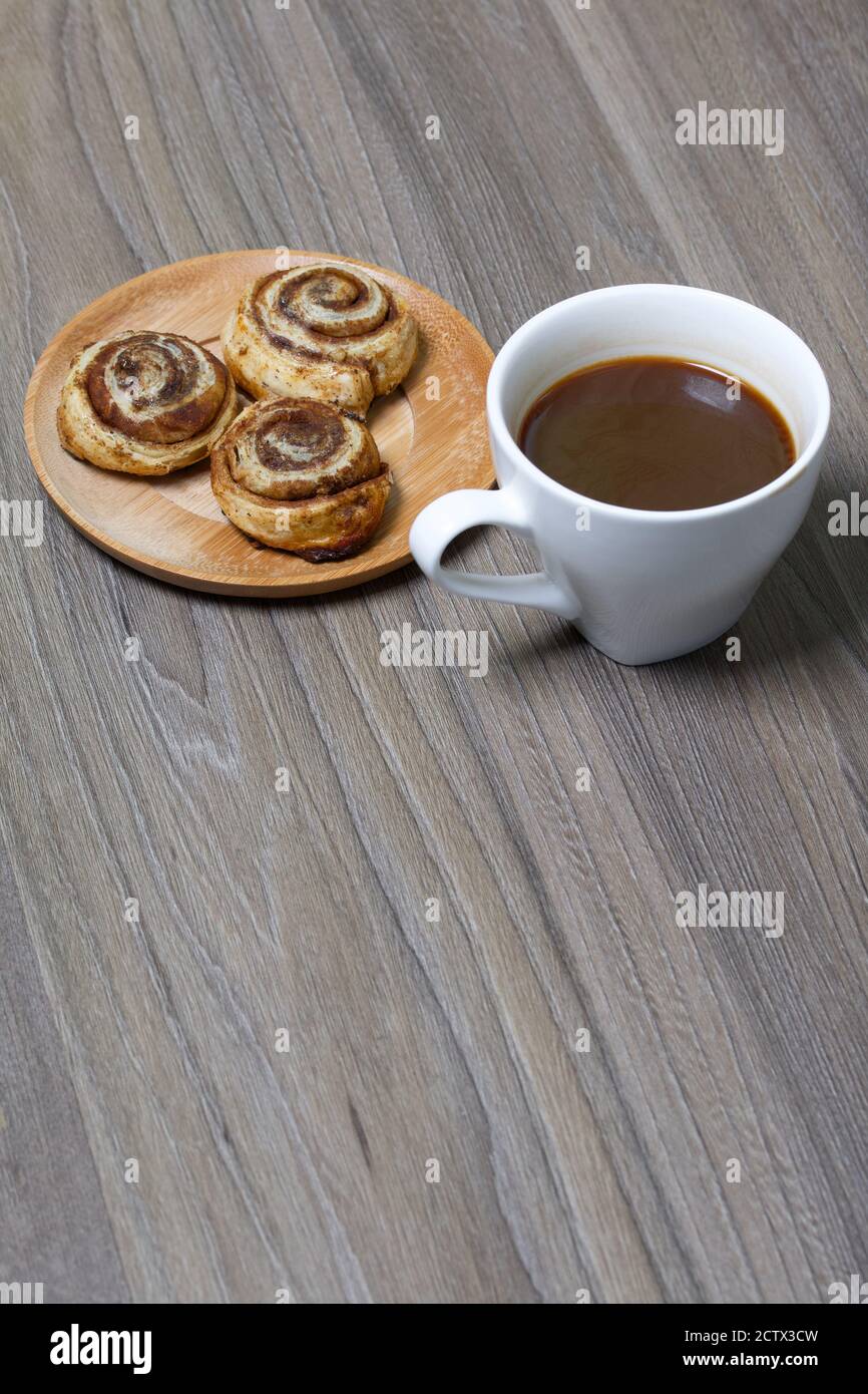 Baked cinnamon burgers. Lie on a plate. Nearby is a cup of coffee Stock ...