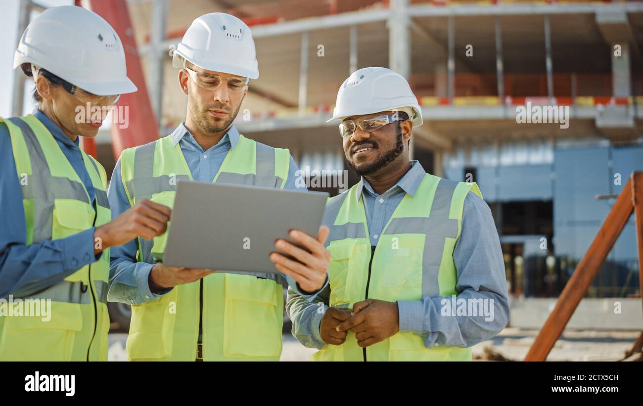 Diverse Team of Specialists Use Laptop Computer on Construction Site ...