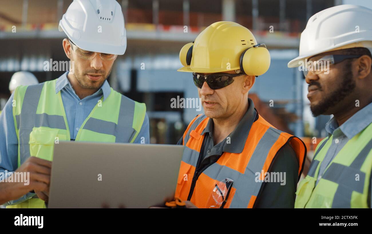 Diverse Team of Specialists Use Laptop Computer on Construction Site ...