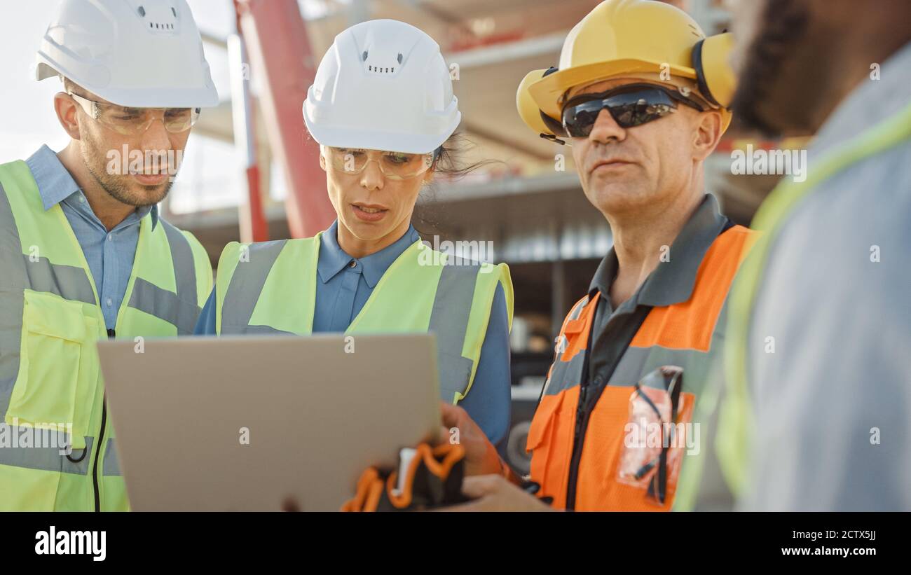 Diverse Team of Specialists Use Laptop Computer on Construction Site ...