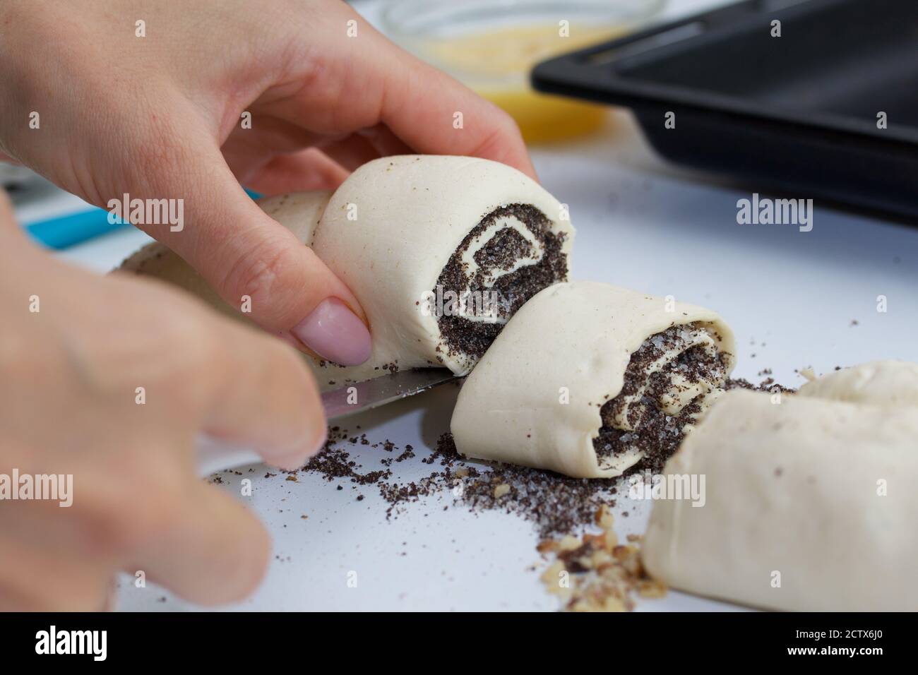 A woman cuts a roll of dough stuffed with poppy. Cooking buns Stock ...