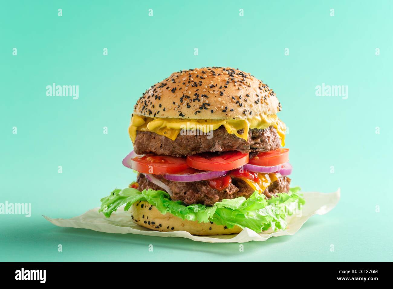 Homemade hamburger on a green colored table. Burger on a piece of ...