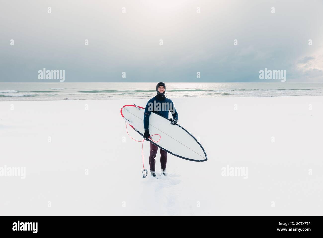 Winter and surfer with surfboard. Snowy beach with male surfer in ...