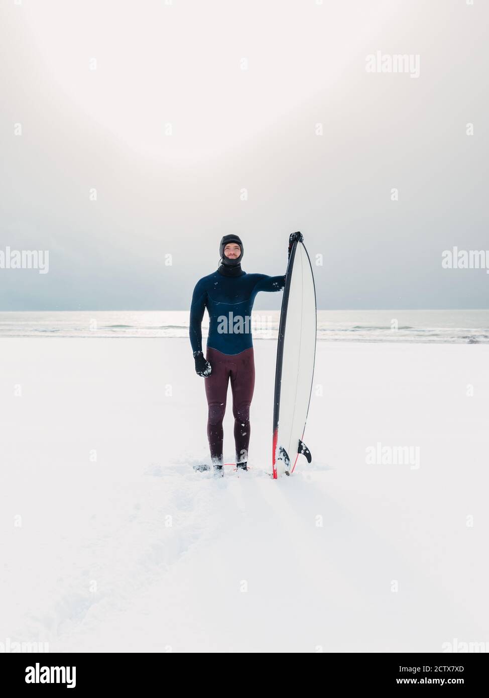 Winter and surfer with surfboard. Snowy beach with male surfer in ...