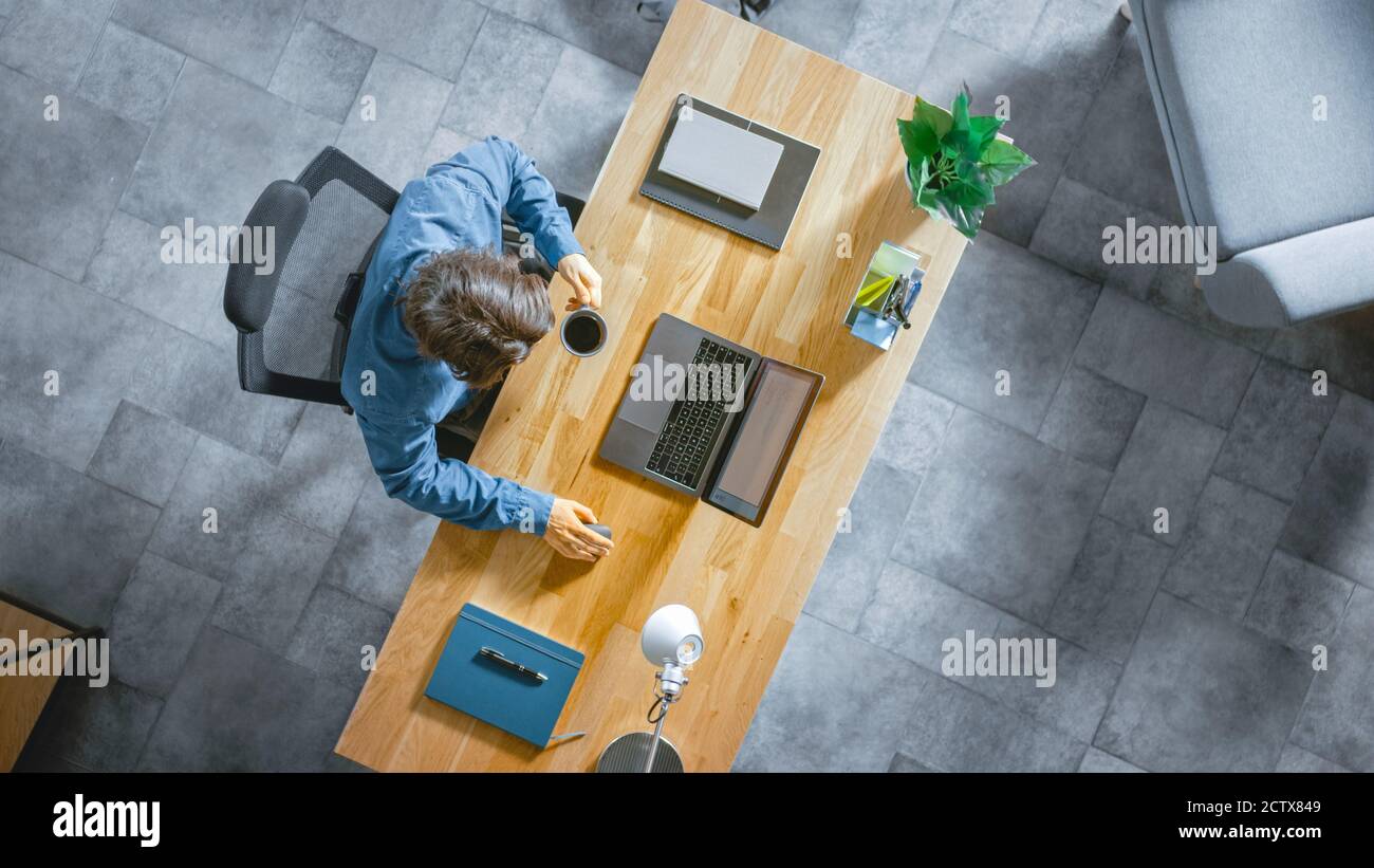Top View Shot: Businessman Sitting at the Wooden Desk Works on a Laptop ...