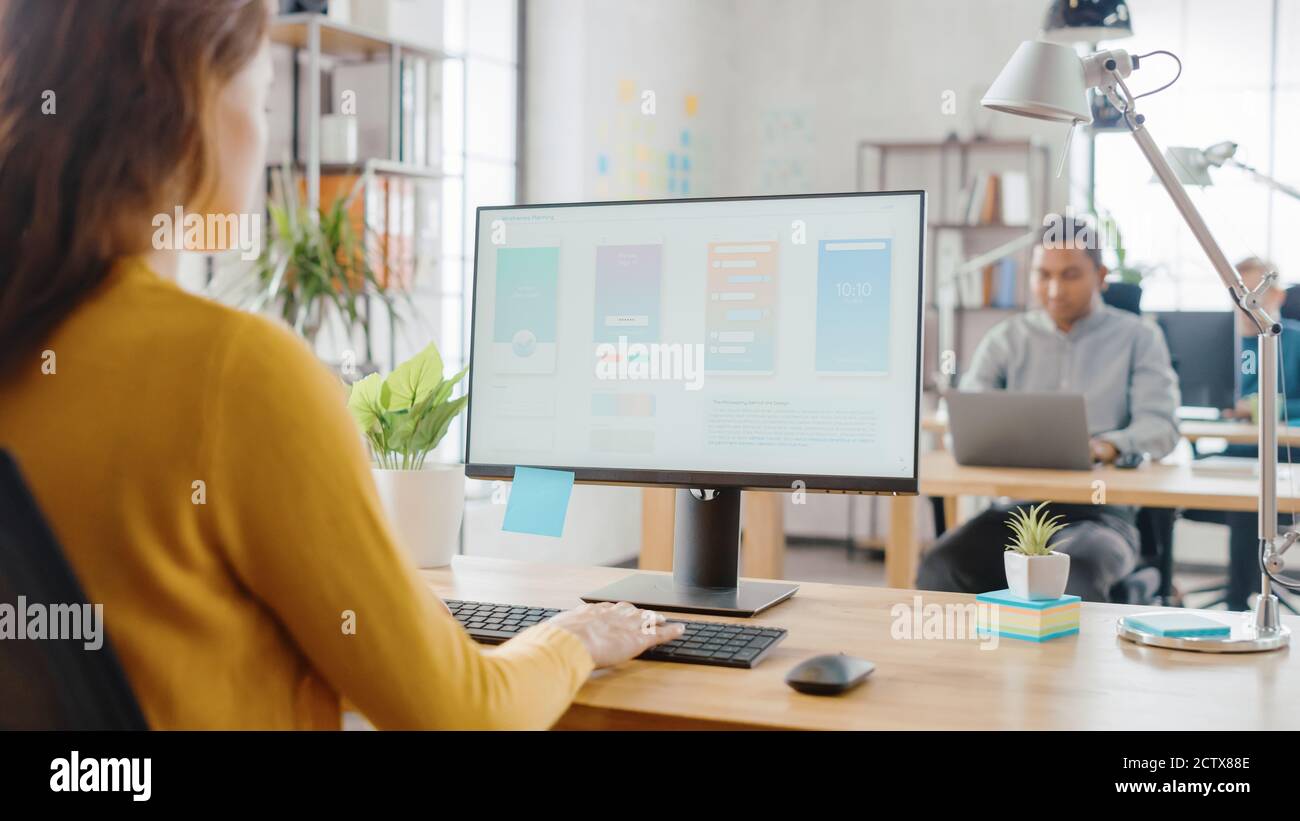 Over the Shoulder: Female Mobile Software Developer Sitting at Her Desk ...