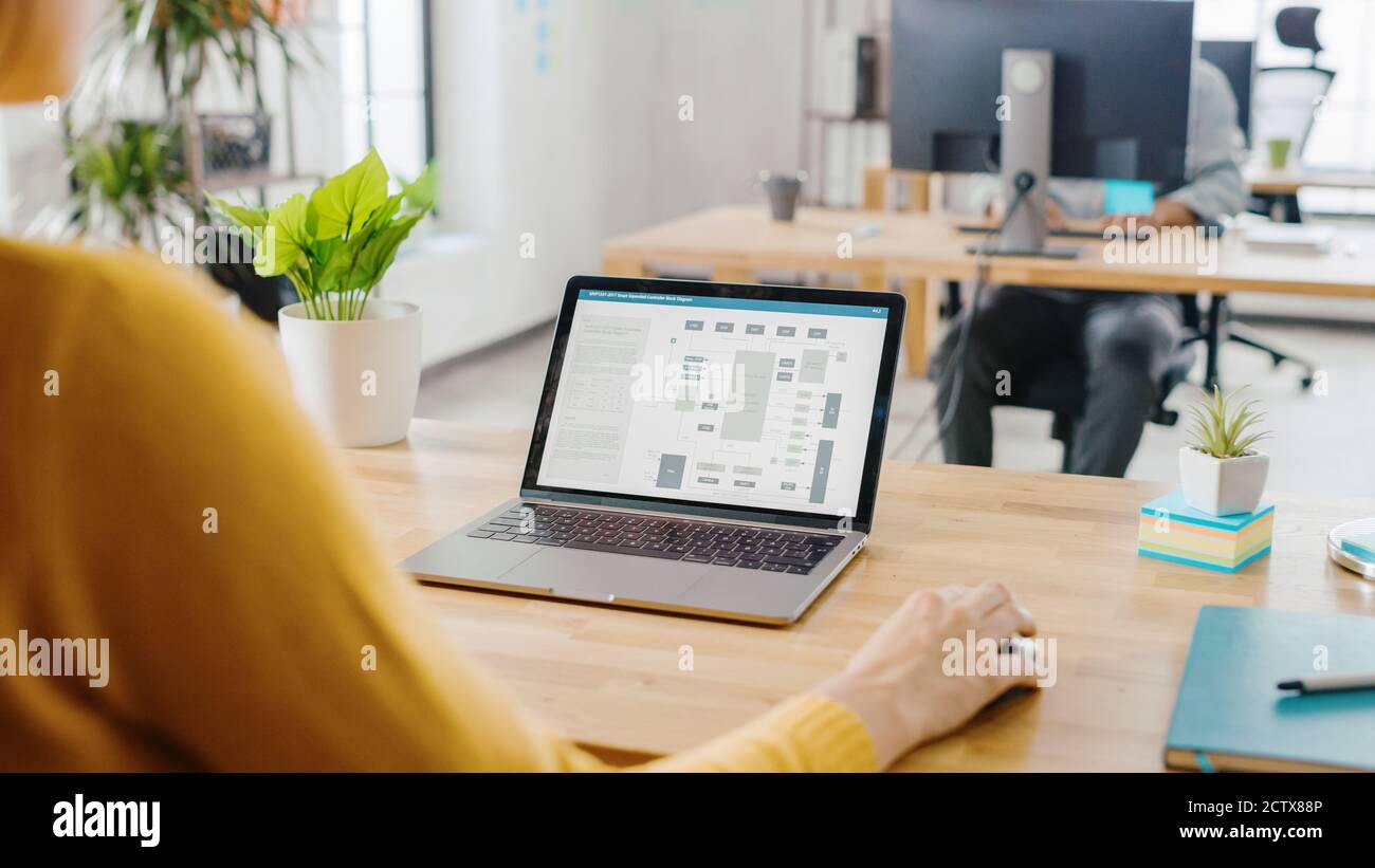 Over the Shoulder: Female Engineer Developer Sitting at Her Desk Using ...