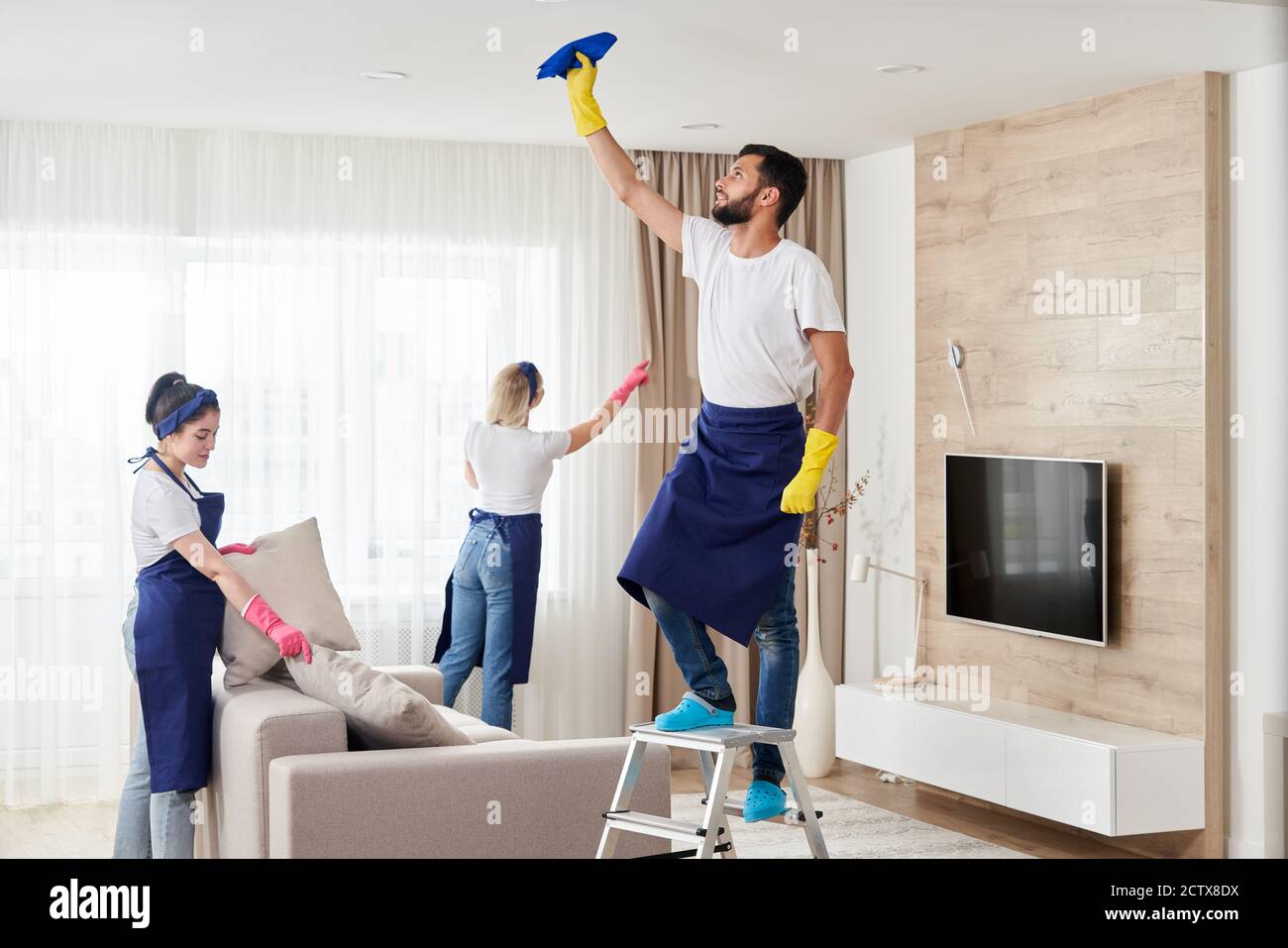 Professional cleaning service team cleans living room in modern ...