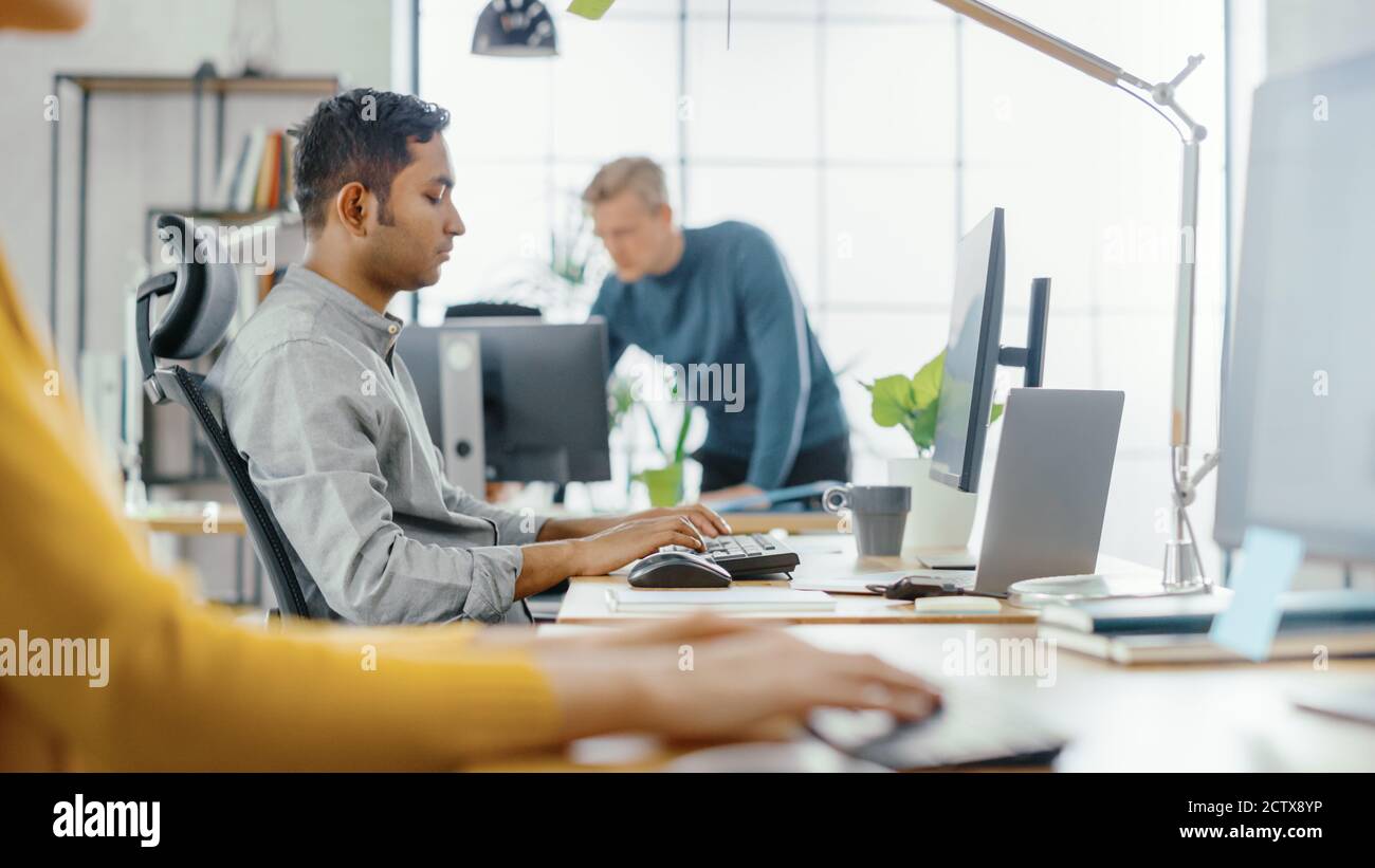 Man Working on Computer. In Foreground Anonymous Young Woman Sitting at ...