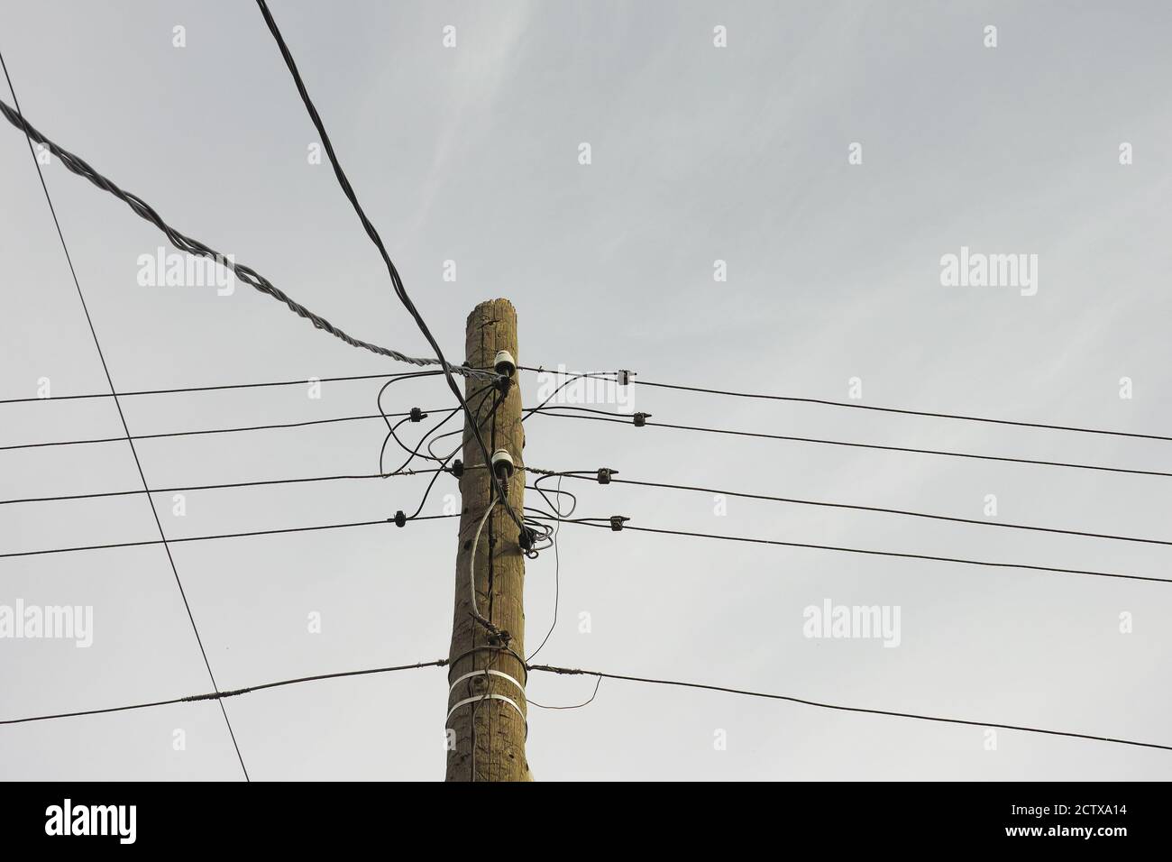 An old electric wooden pole with electricity cables hanging on it ...