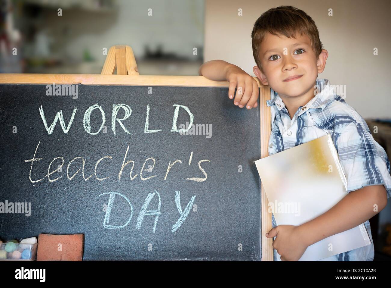 World Teacher's Day greeting, pupil boy near the chalkboard, chalk ...