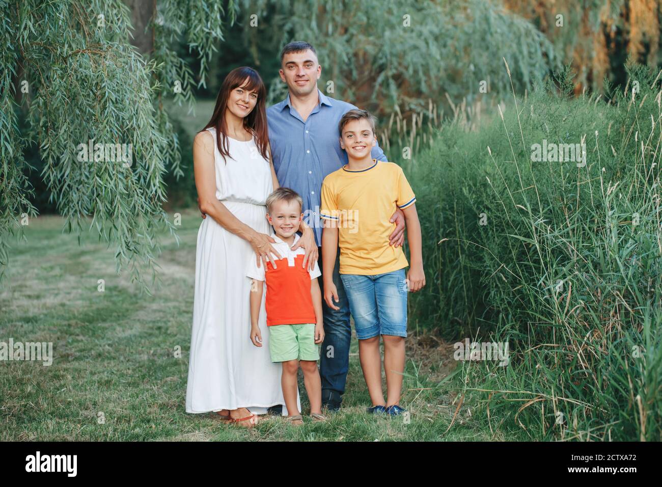 Beautiful happy Caucasian family of four people in park on summer day ...