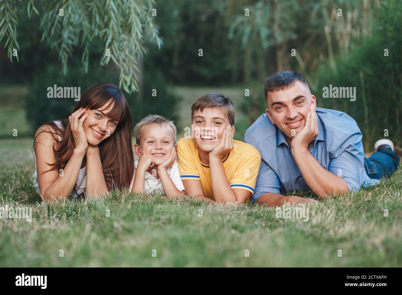 Beautiful happy Caucasian family of four people in park on summer day ...