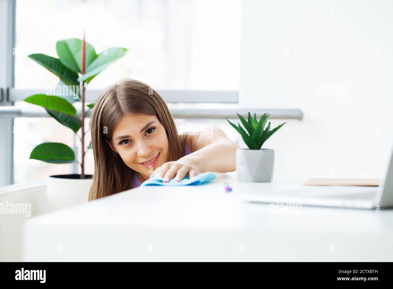 Cleaner tidies up the computer desk in the office Stock Photo - Alamy