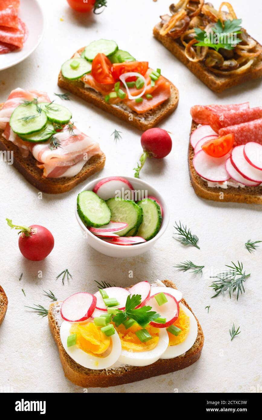 Open sandwiches with meat, vegetables, seafood on light stone ...