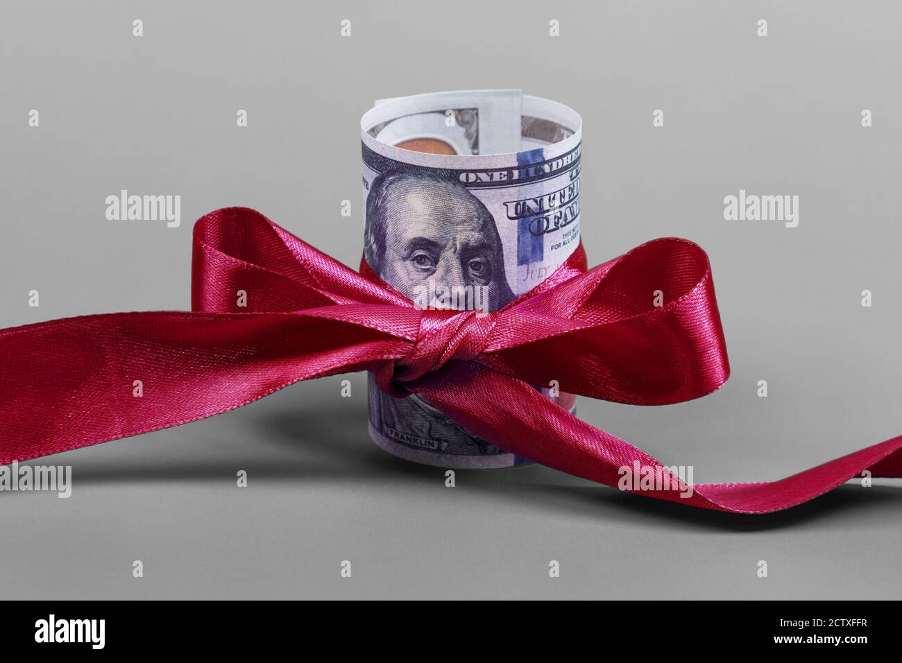 Hundred dollar bill tied with red bow on grey background. Money, gift ...