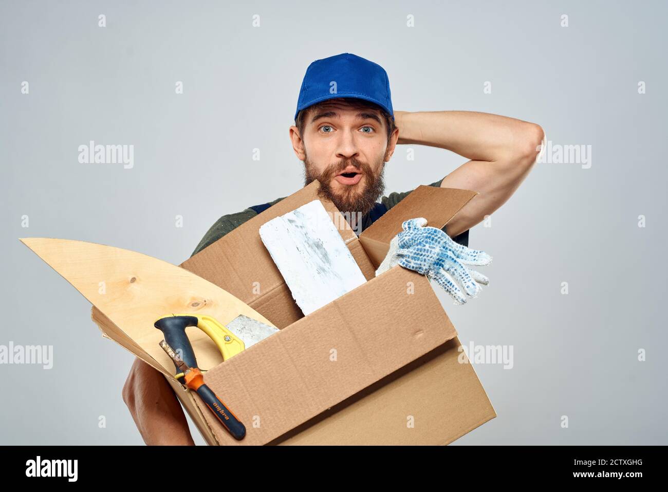 man in work uniform with box in hands tools lifestyle light background ...