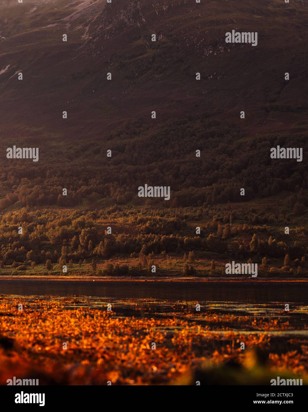 Loch Sunset casting over the mountain onto the loch Stock Photo - Alamy