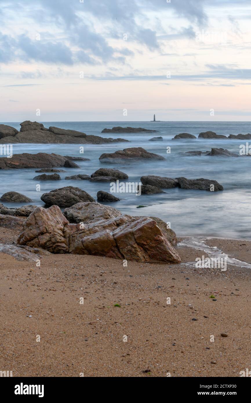 Rocks on the beach in the evening with moving water which brings an ...