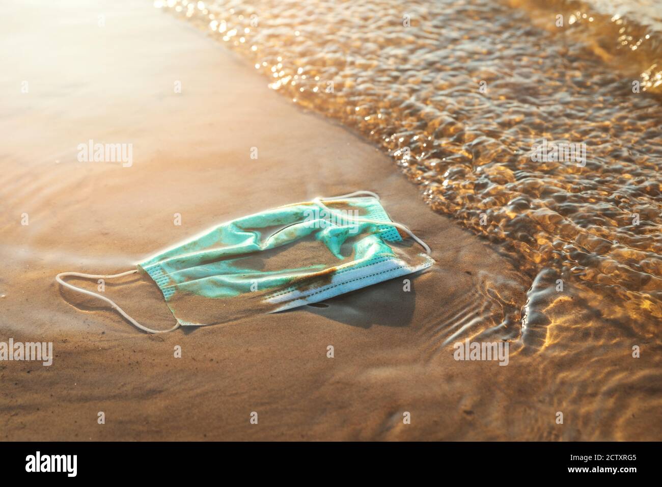 medical waste - protective face mask in the water on the beach coast ...