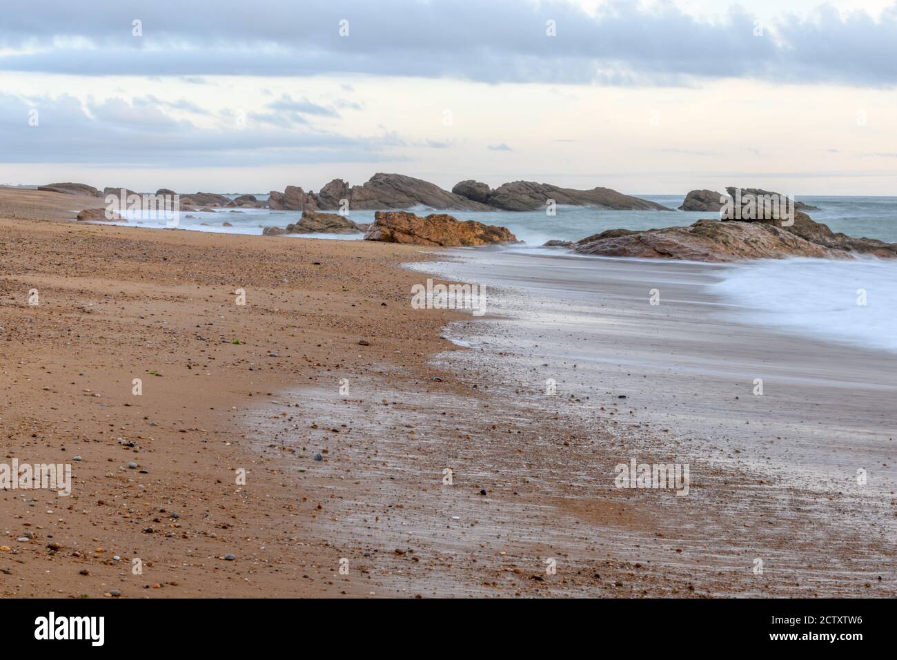 Rocks on the beach in the evening with moving water which brings an ...