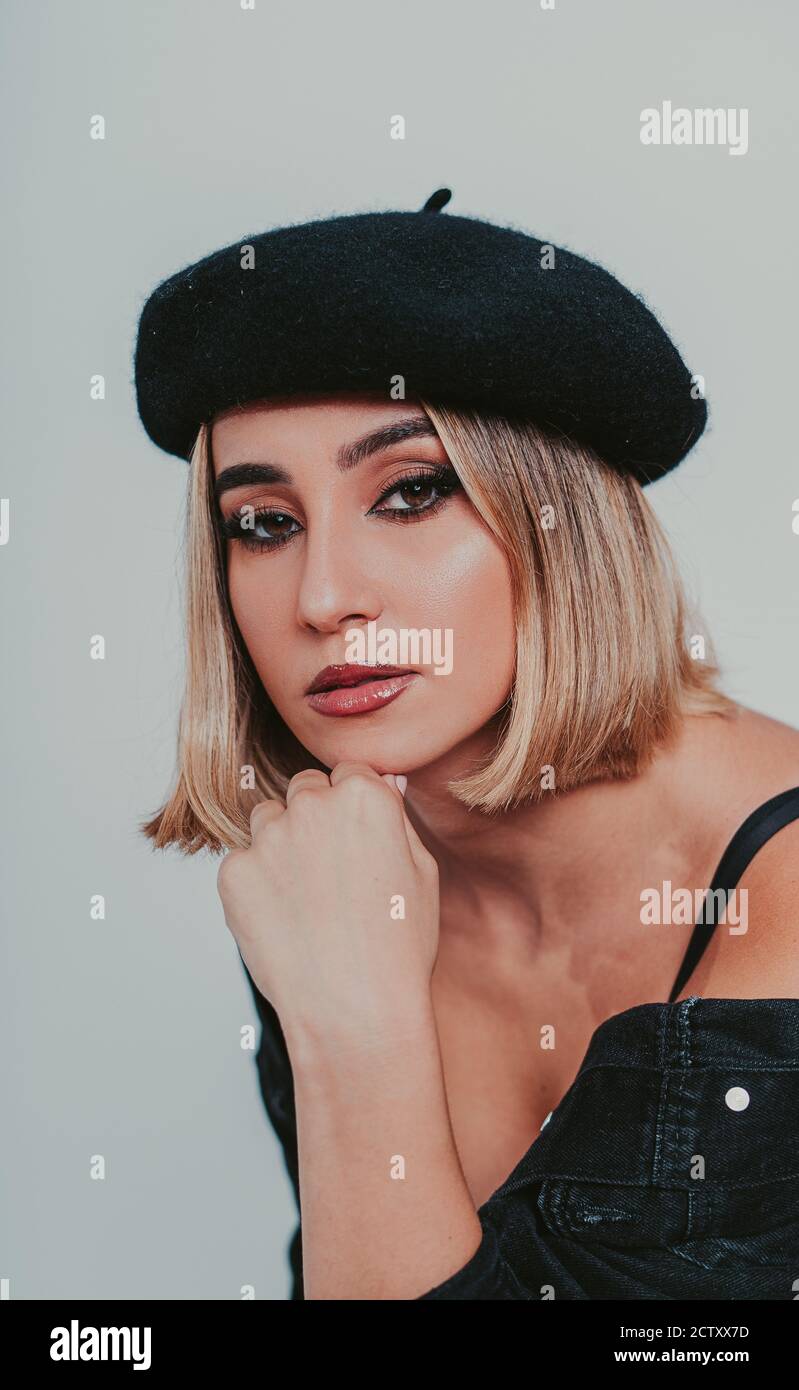 Portrait of a confident female wearing a beret and a black denim jacket ...