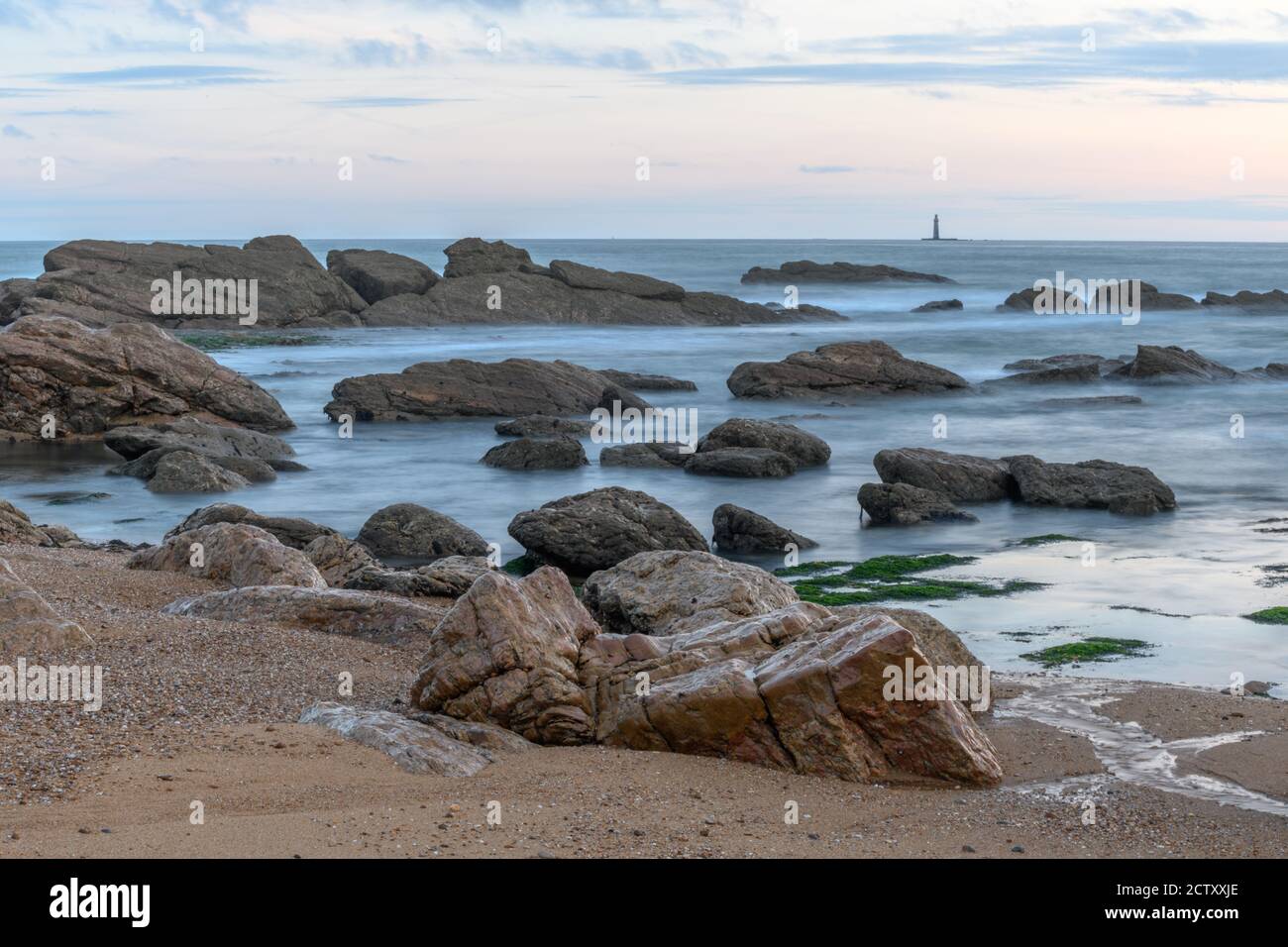 Rocks on the beach in the evening with moving water which brings an ...