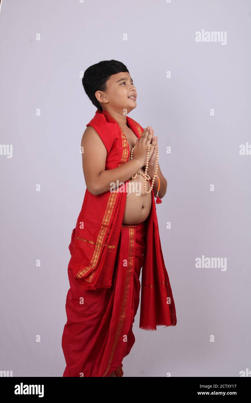 Young boy wearing Indian ethnic wear in namaste pose with rosary ...