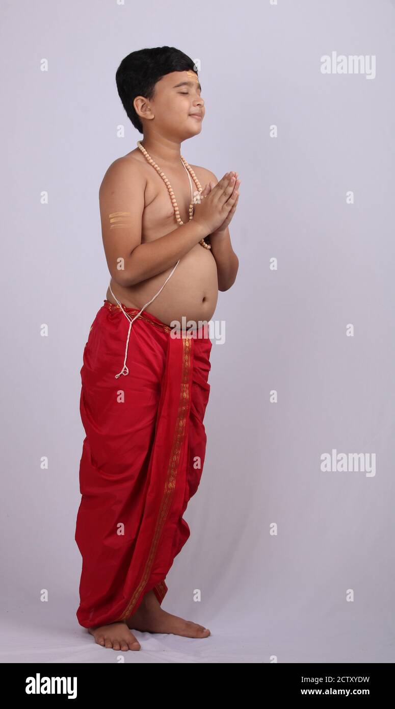 Young boy wearing Indian ethnic wear in namaste pose with rosary ...