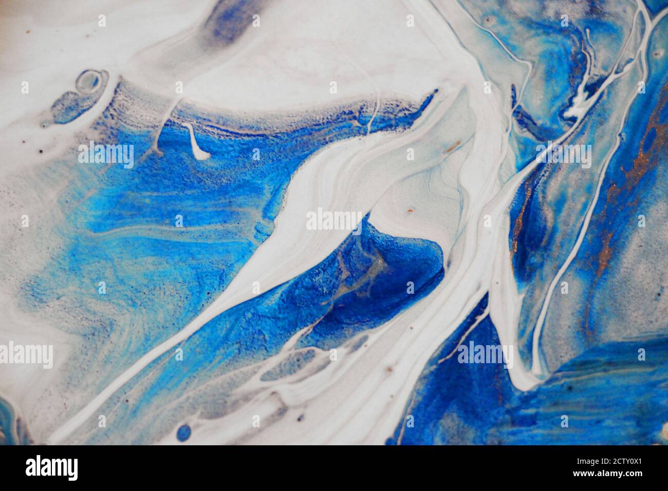 Swirl of blue dye dissolved in light gray and golden pigment . acrylic ...