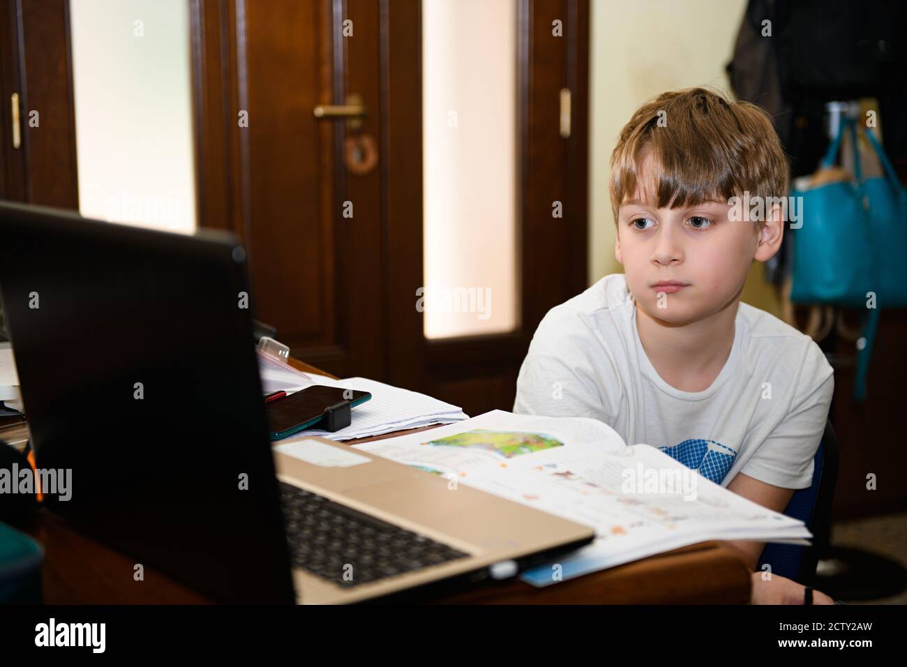 Tired or sad student boy with laptop computer sitting near a desk at ...