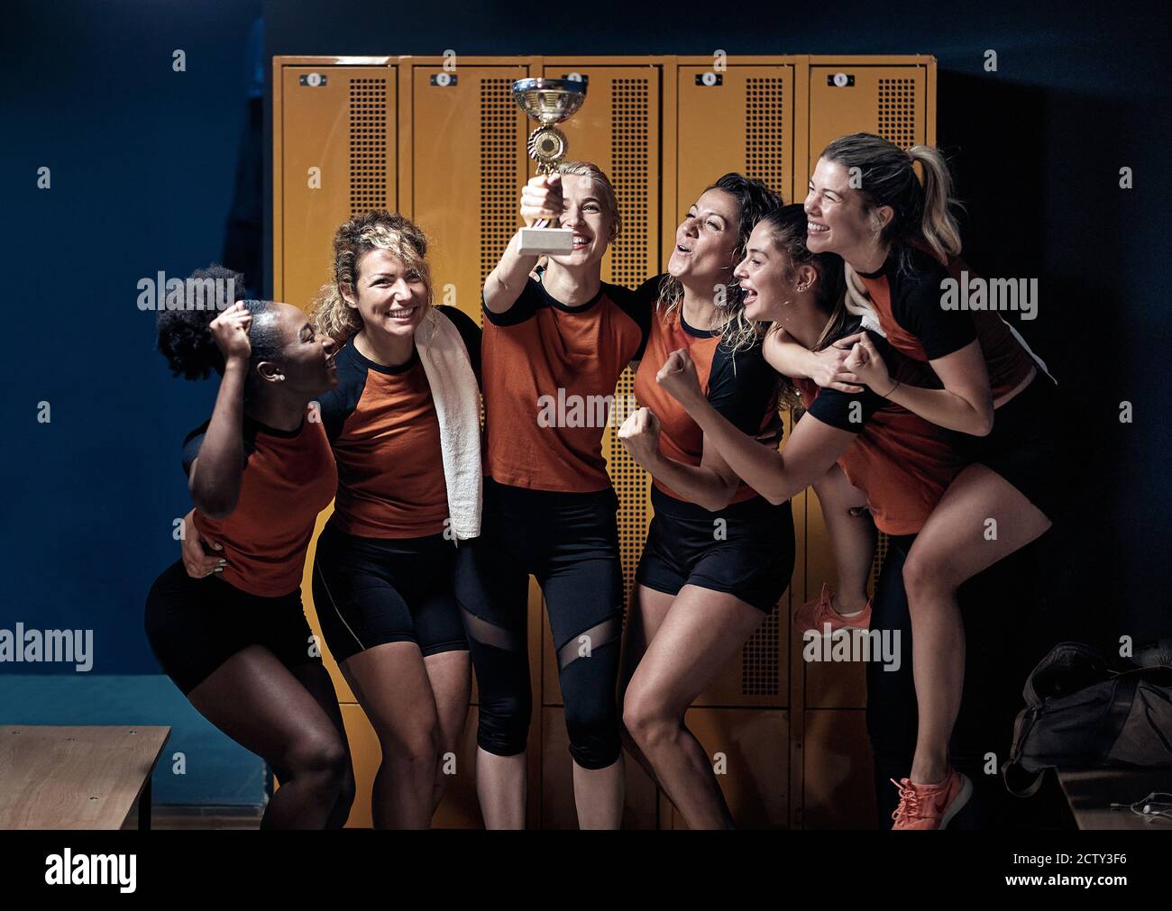 Female team celebrating the won cup in a locker room Stock Photo - Alamy