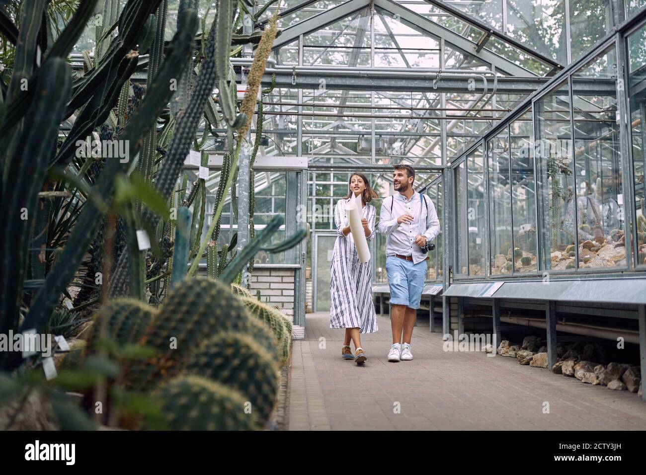 Young colleagues enjoying cactuses and the walk in a botanical garden ...