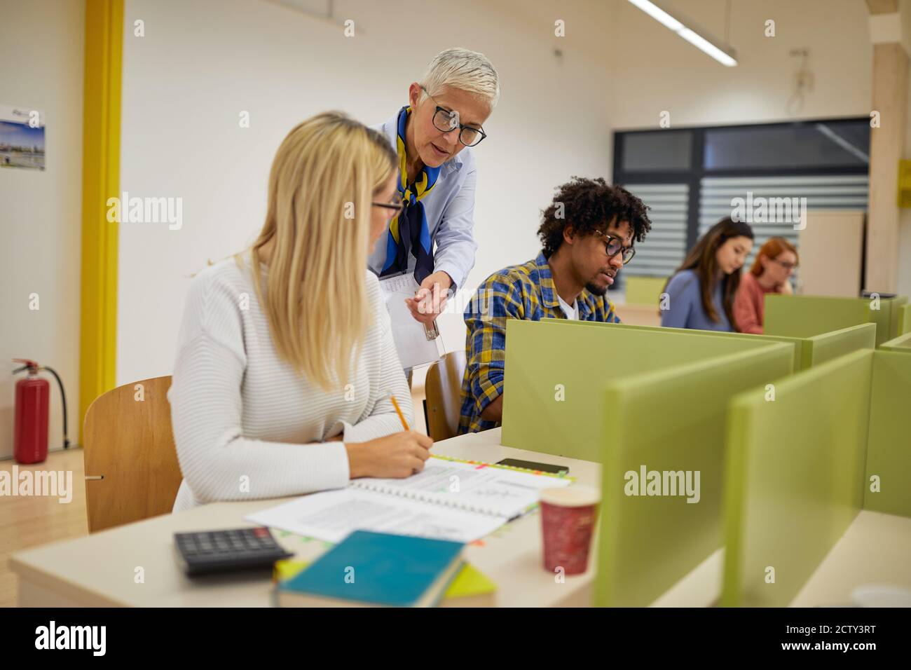 Female professor correcting students work in the university classroom ...